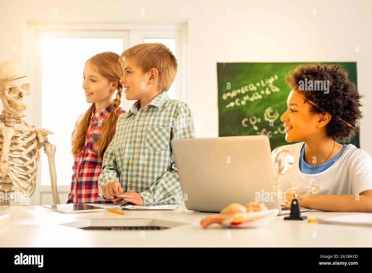 Positive delighted children studying with great interest Stock Photo ...