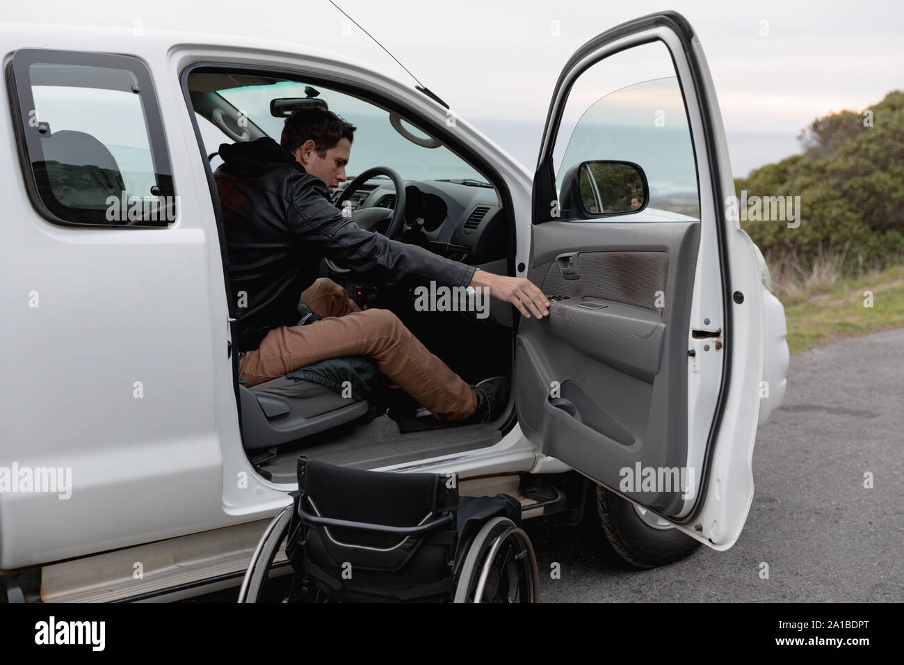 Disabled man getting out of a car into a wheelchair Stock Photo - Alamy