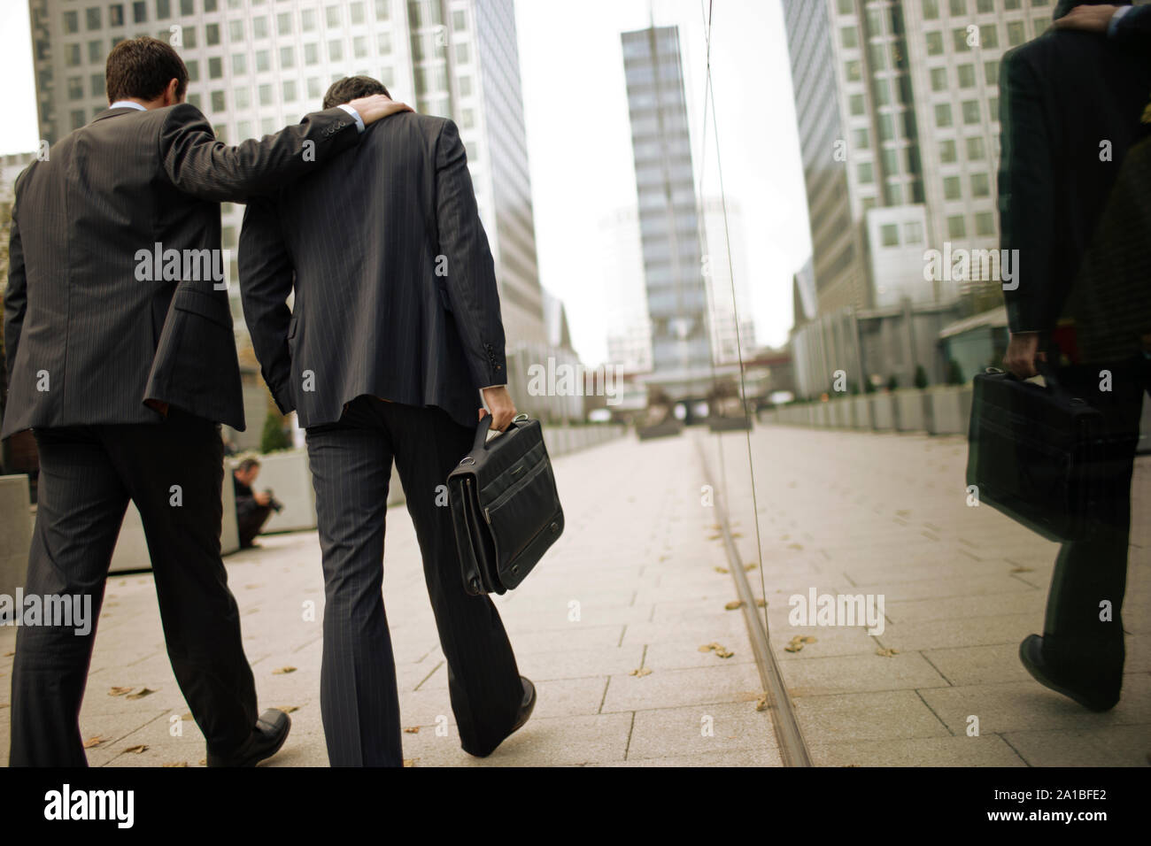 Two businessmen walking home together through city streets Stock Photo ...