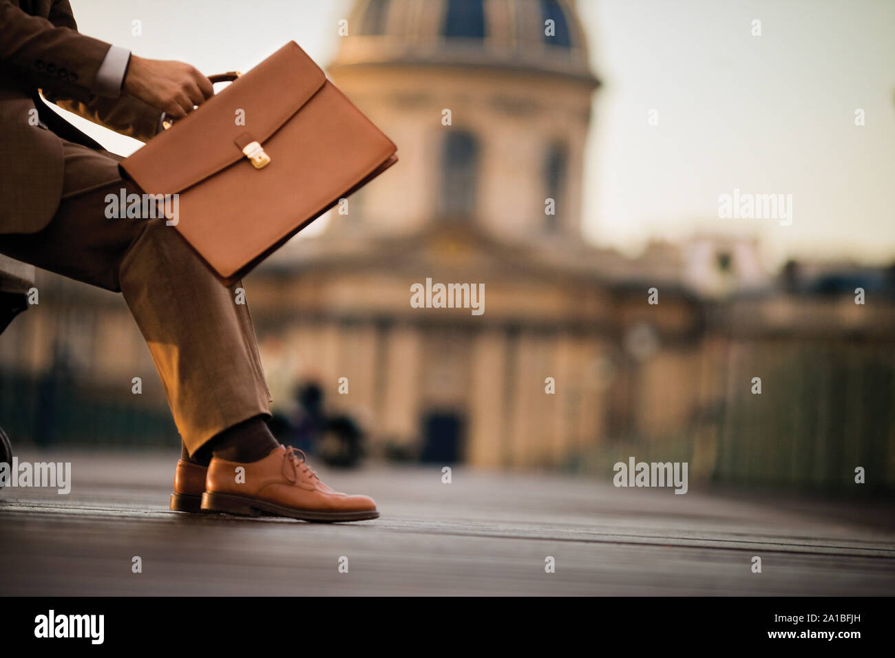 Businessman holds his briefcase as he sits in a plaza Stock Photo - Alamy