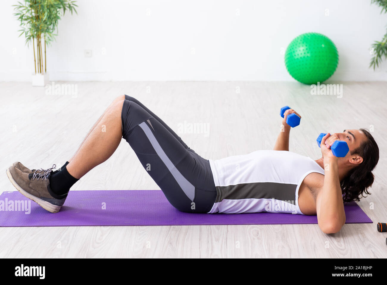 The young handsome man doing sport exercises indoors Stock Photo - Alamy