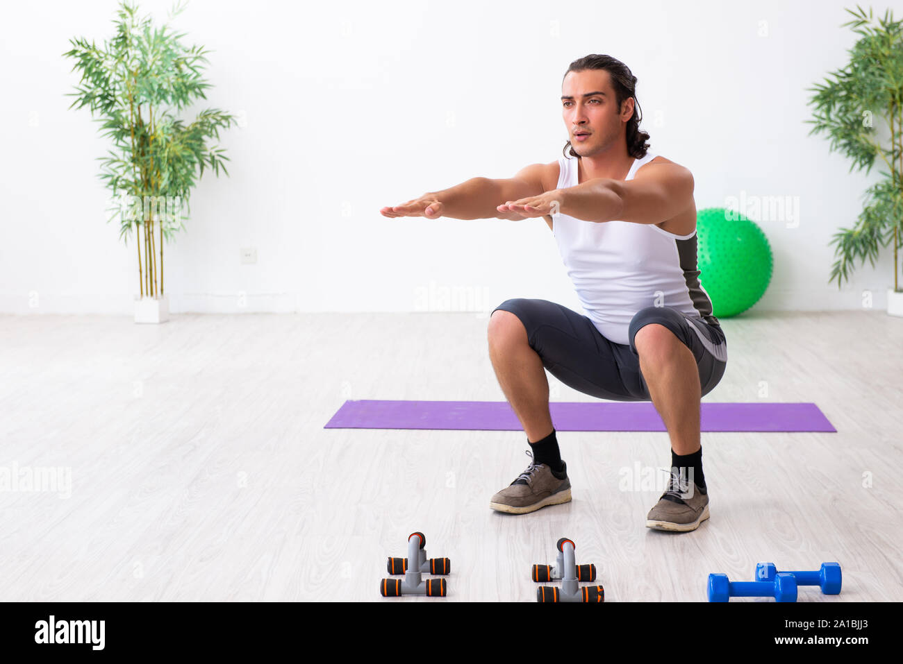 The young handsome man doing sport exercises indoors Stock Photo - Alamy