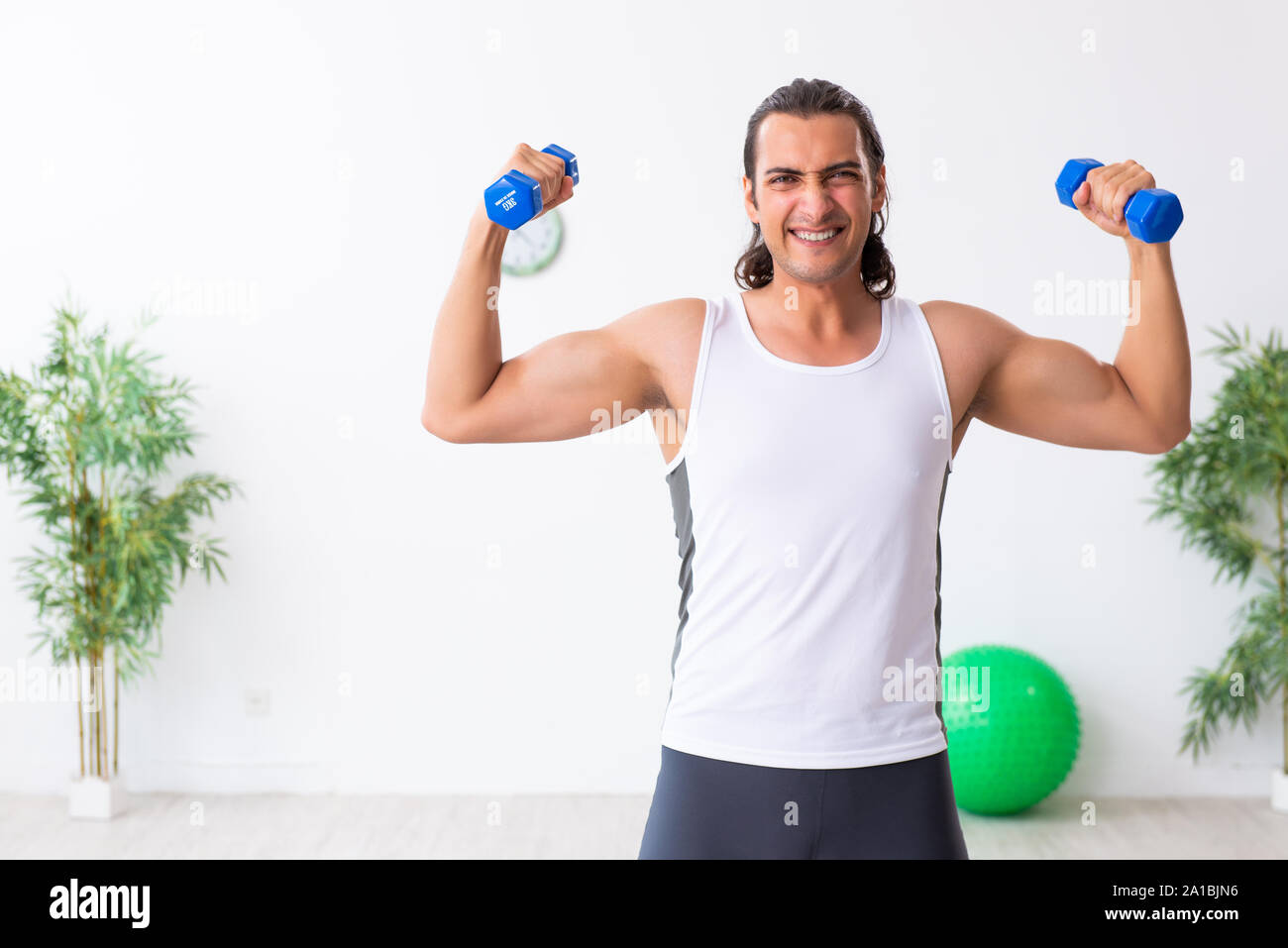 The young handsome man doing sport exercises indoors Stock Photo - Alamy