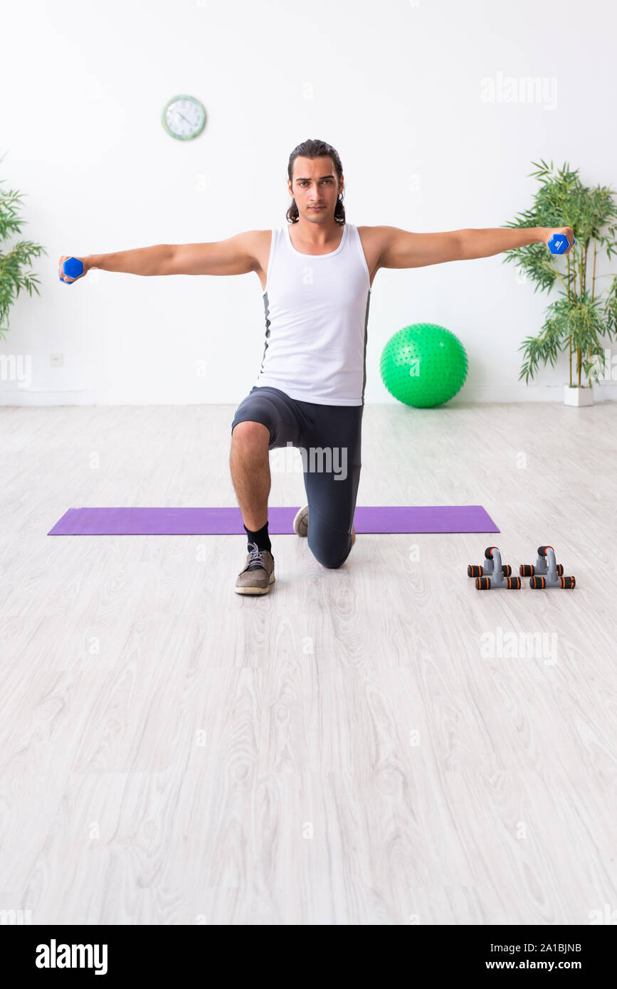 The young handsome man doing sport exercises indoors Stock Photo - Alamy