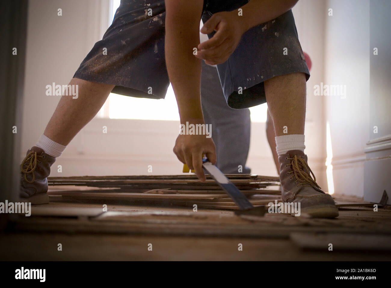 Builder scraping floorboards with a hand tool Stock Photo - Alamy
