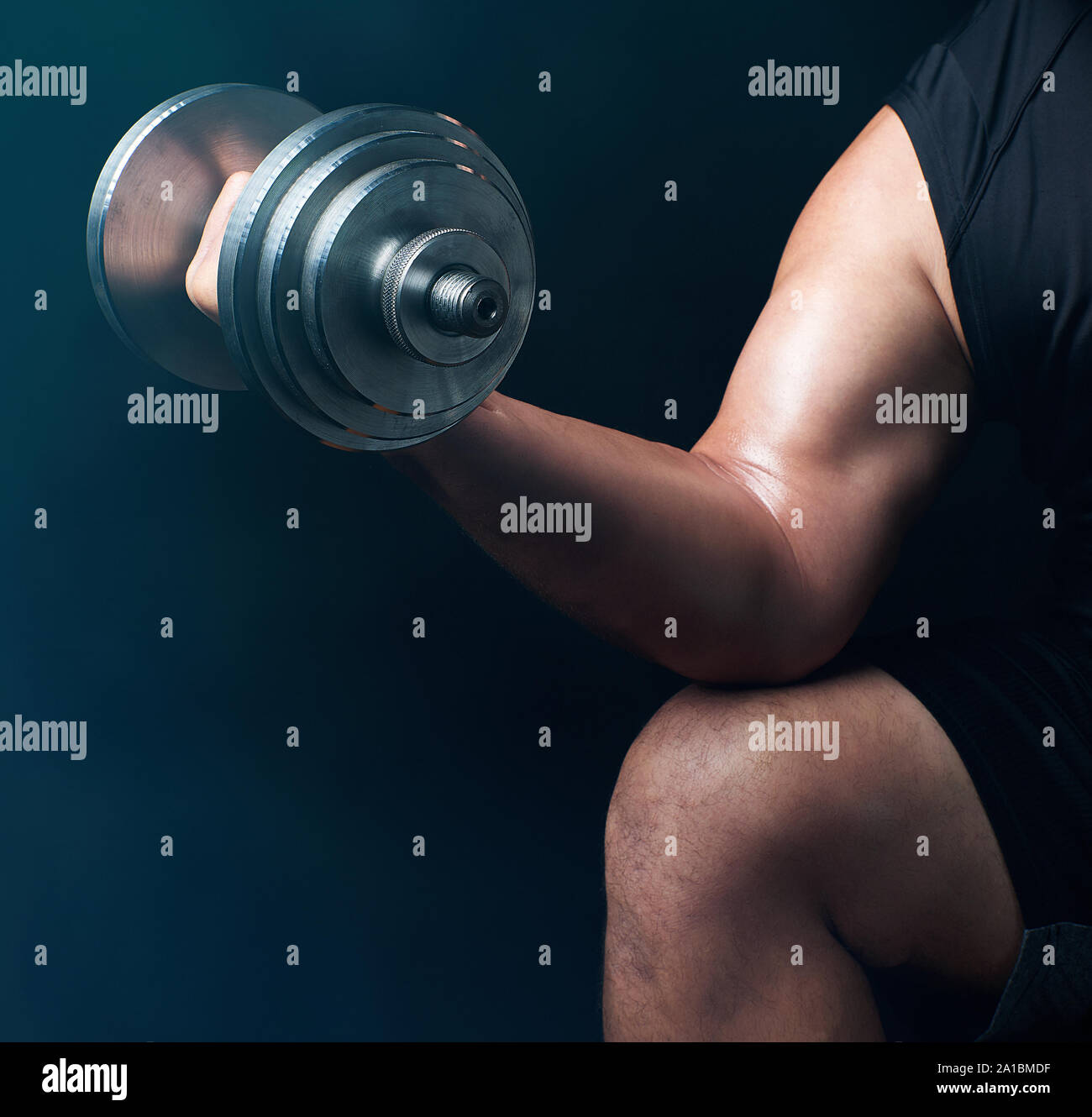 hand of a man with big biceps holds a steel type-setting dumbbell, low ...