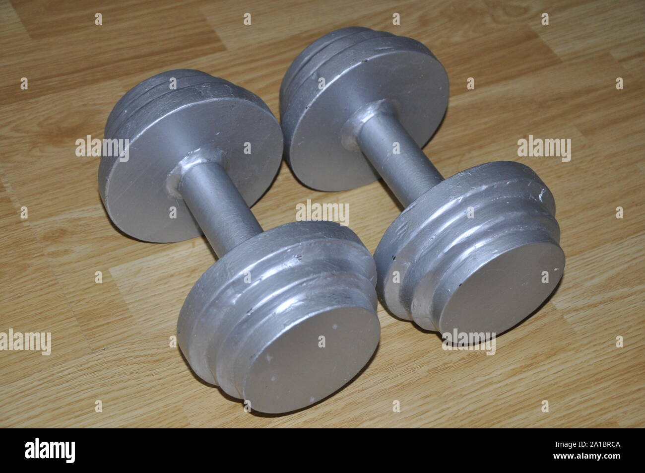 A pair of self-made metal dumbbells on oak flooring Stock Photo - Alamy