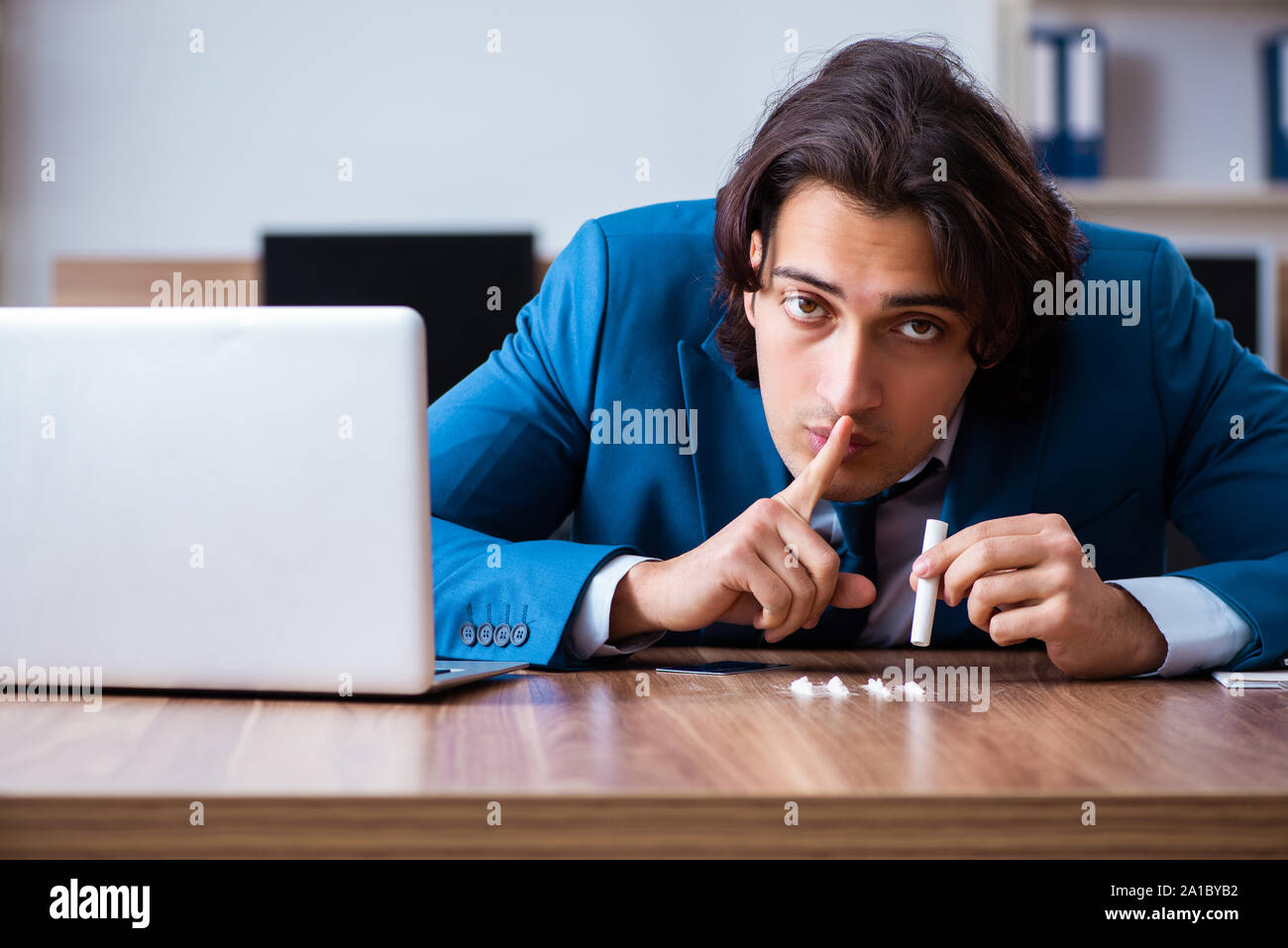 The young man having problems with narcotics at workplace Stock Photo ...