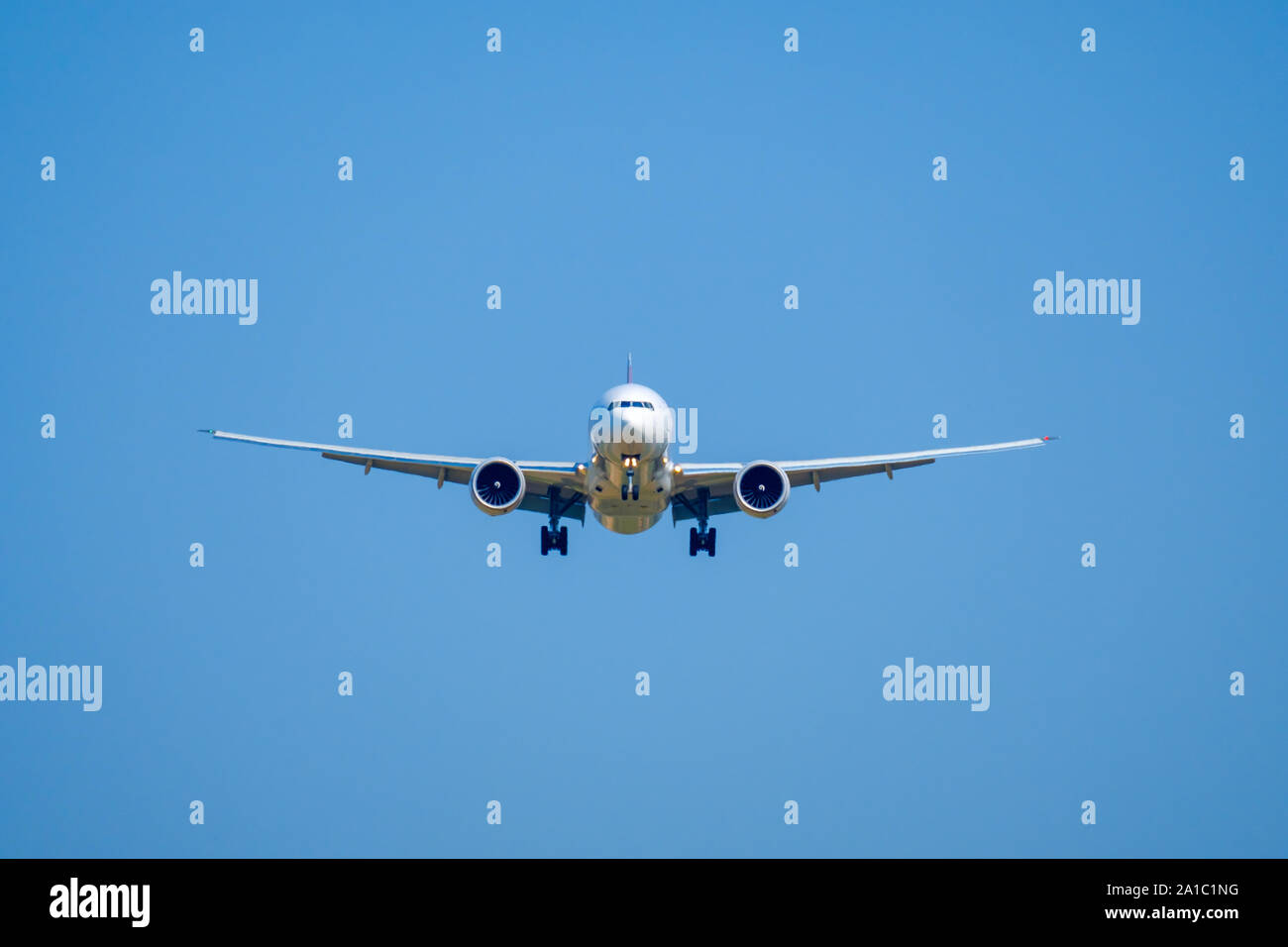 Passenger airplane flying in blue sky, front view Stock Photo - Alamy