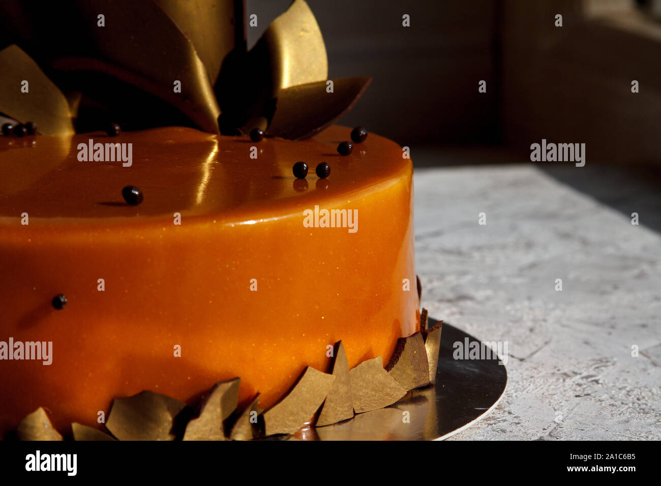 Caramel icing cake decorated with gold foil and chocolate drops on ...