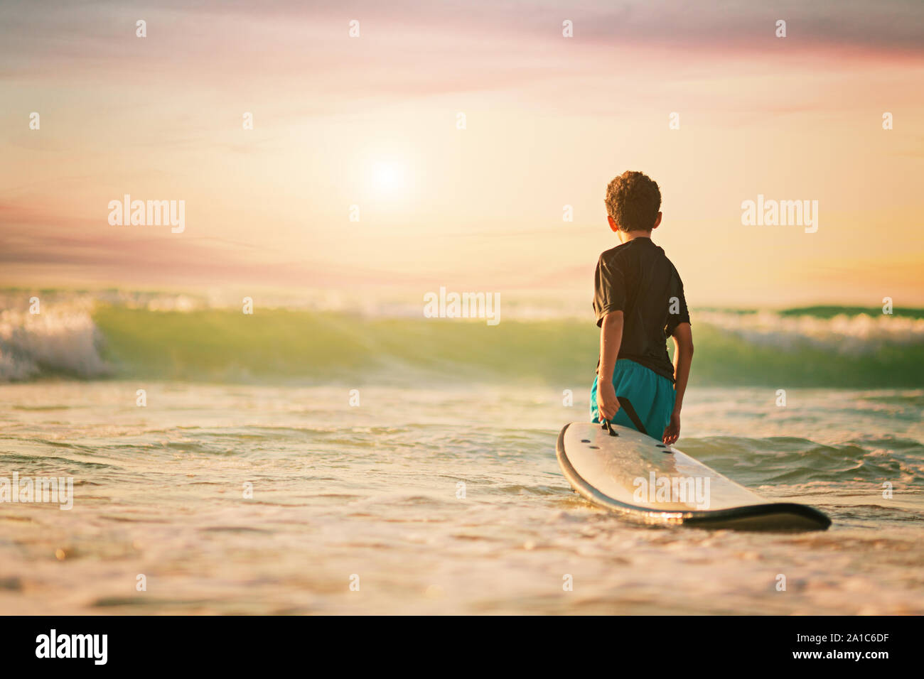 Back view of the little surfer boy surfing lifestyle relaxing holding ...