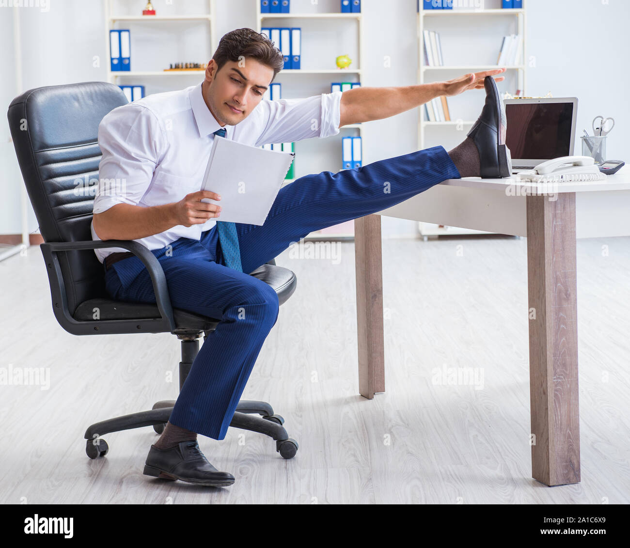 The young businessman doing sports stretching at workplace Stock Photo ...