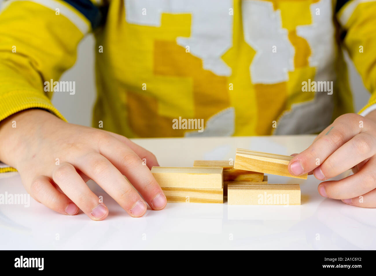 Child hands playing with wooden blocks the unstable tower. Building ...