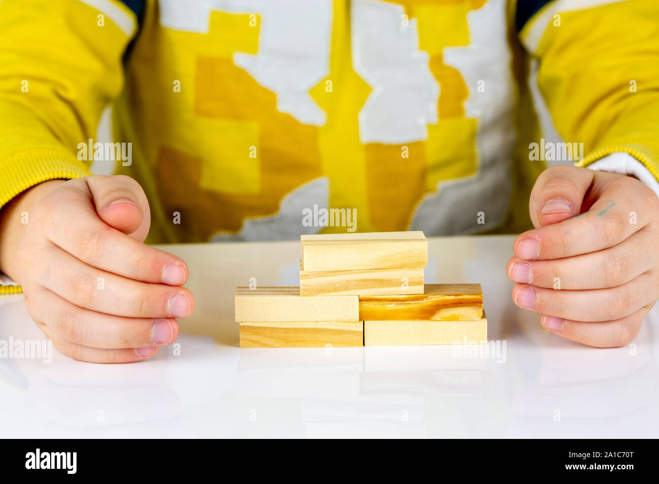 Child hands playing with wooden blocks the unstable tower. Building ...