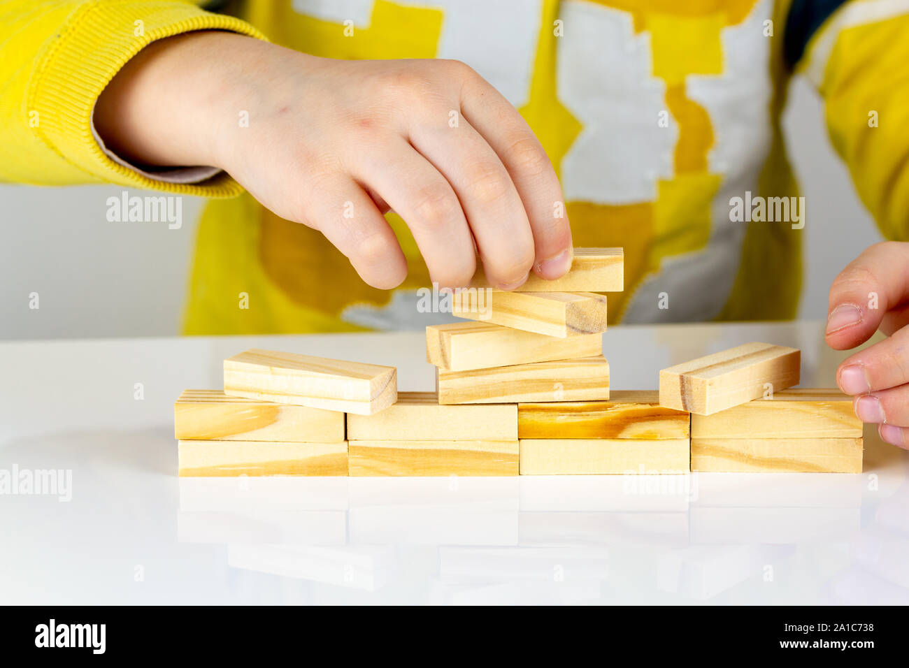 Child hands playing with wooden blocks the unstable tower. Building ...