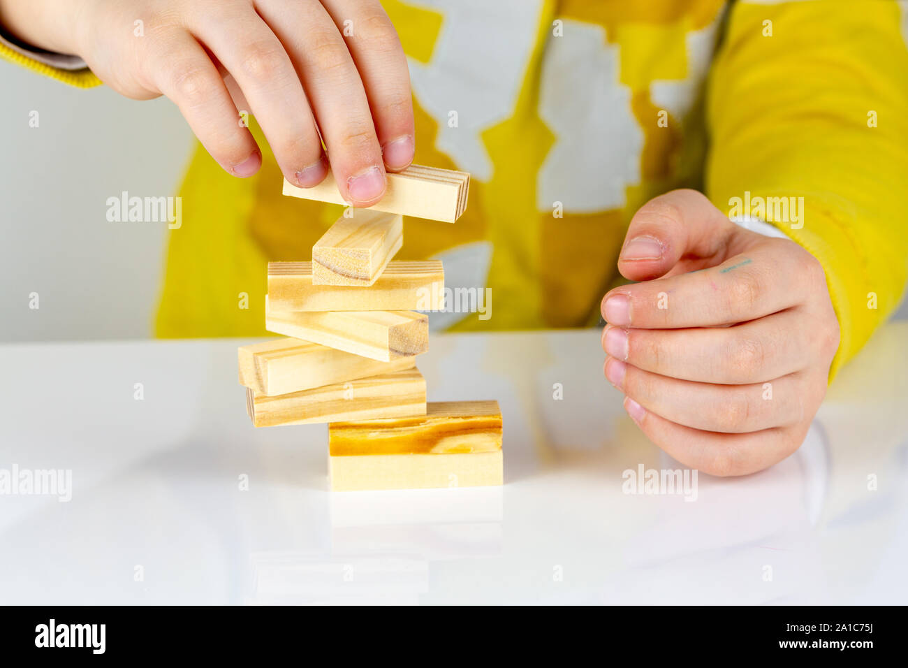 Child hands playing with wooden blocks the unstable tower. Building ...