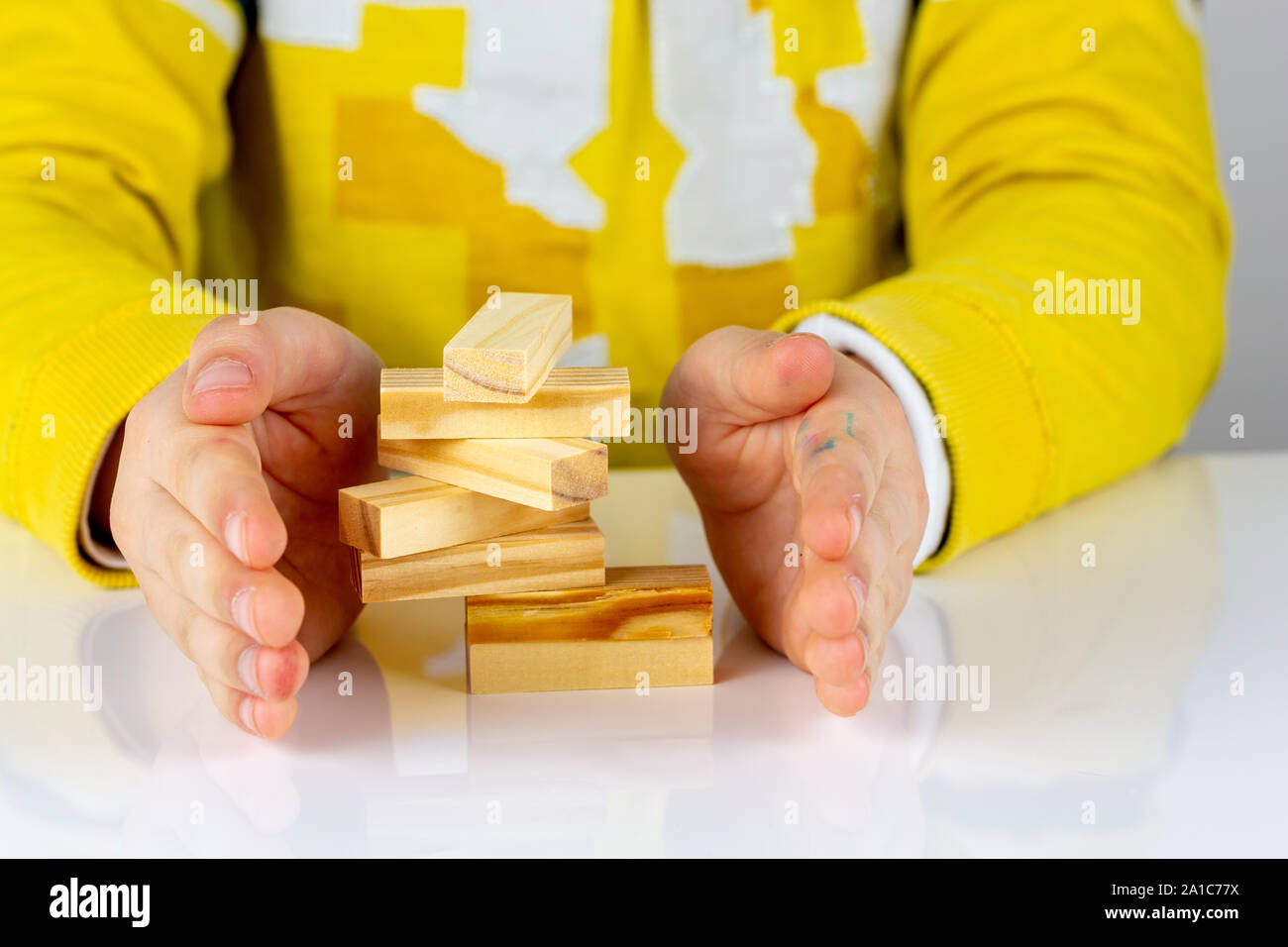 Child hands playing with wooden blocks the unstable tower. Building ...