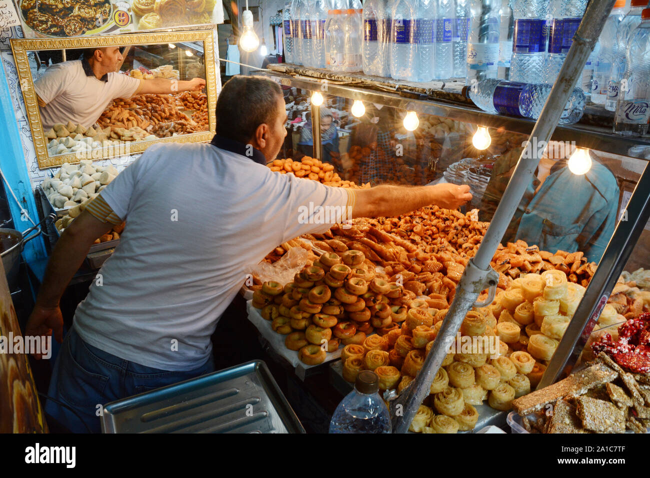 A food merchant selling biscuits and pastries serves a waiting customer ...