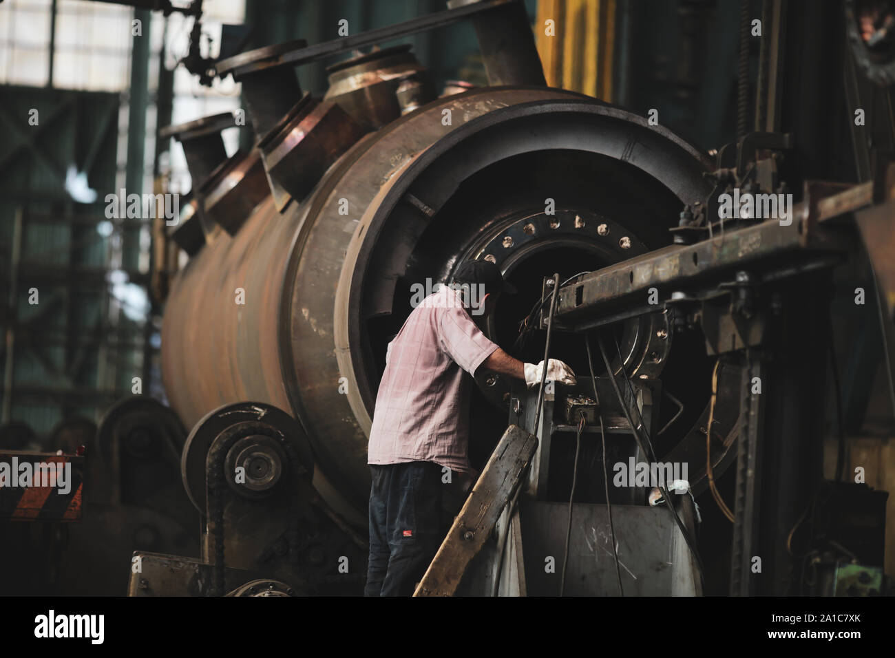 Senior worker in a dirty and old but still functioning metal works, old ...