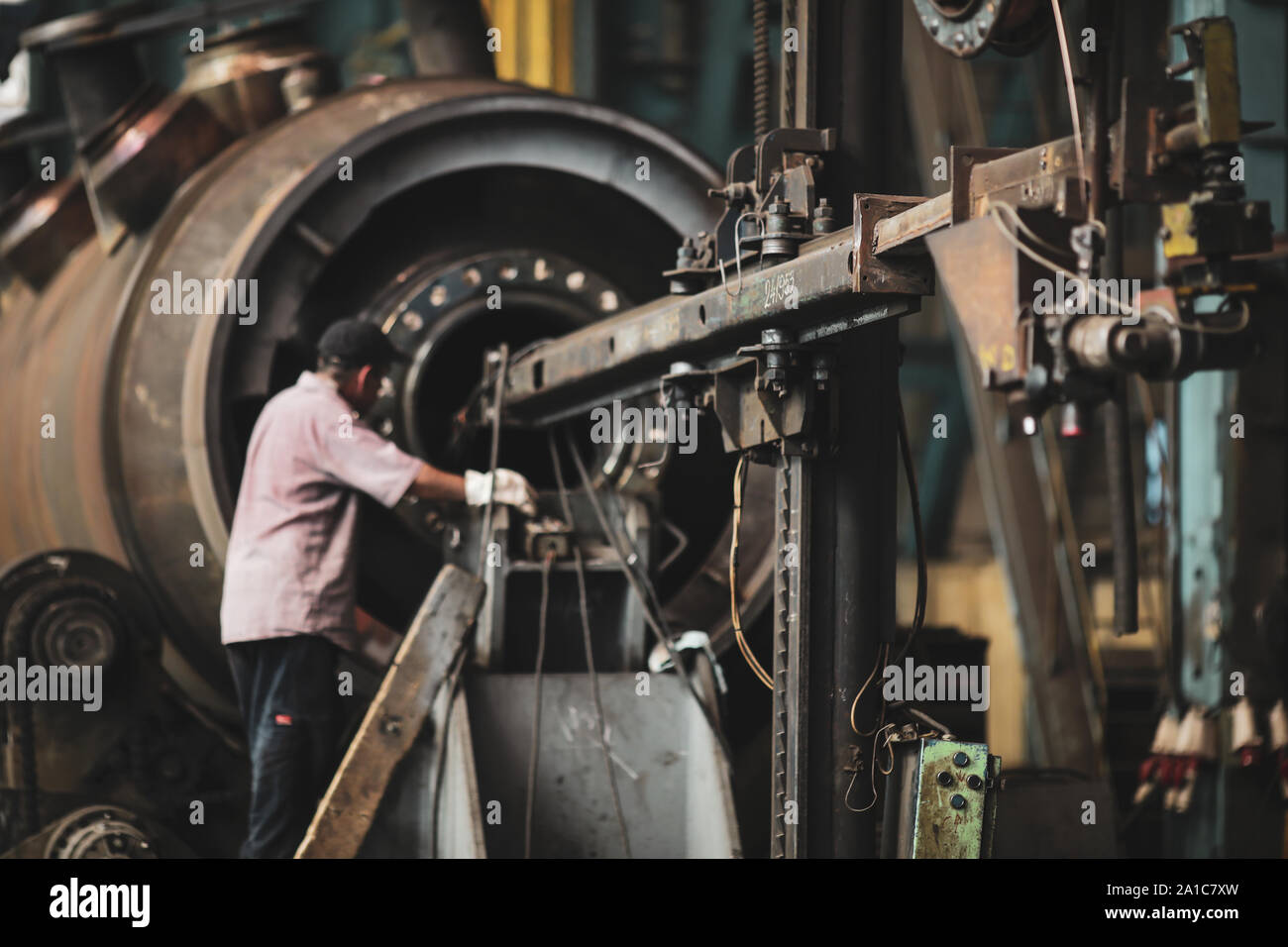 Senior worker in a dirty and old but still functioning metal works, old ...