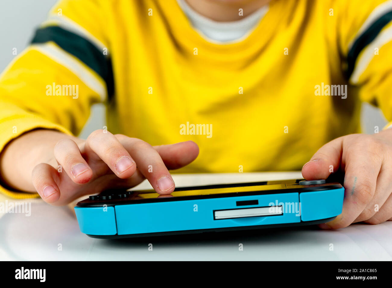 Young child playing on a game console on a white desk Stock Photo - Alamy