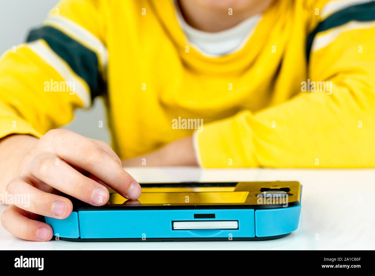 Young child playing on a game console on a white desk Stock Photo - Alamy