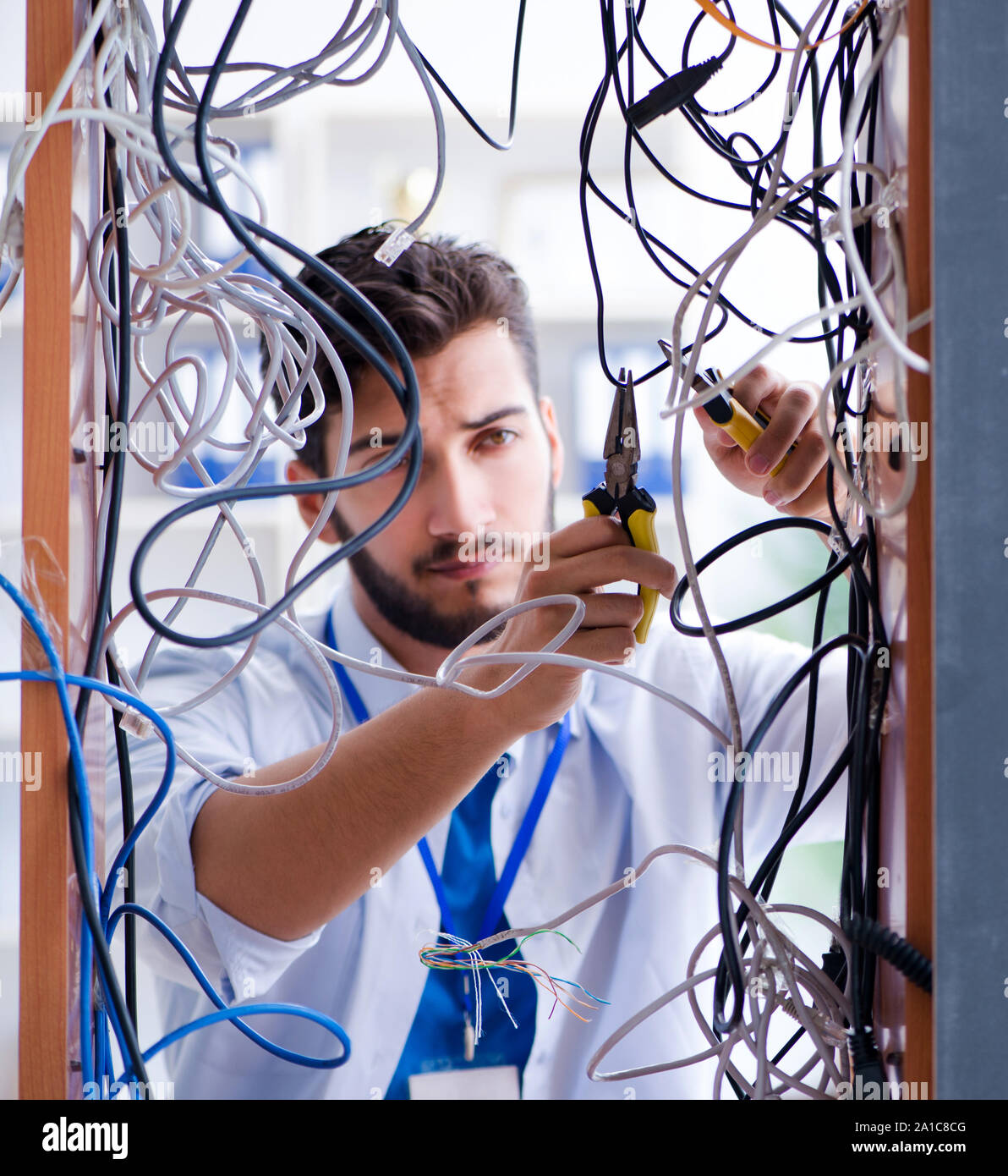 The electrician trying to untangle wires in repair concept Stock Photo ...