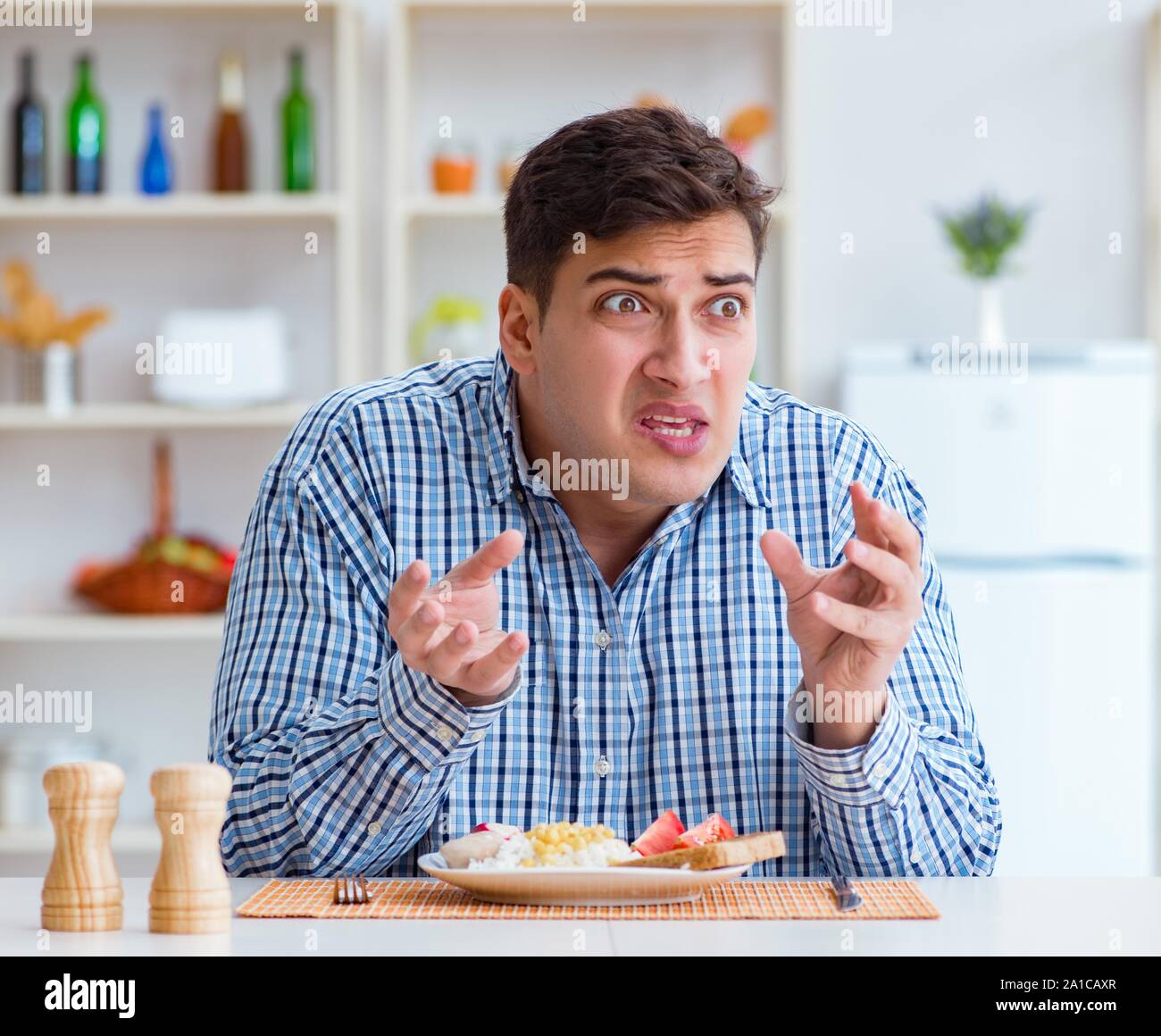 The young husband eating tasteless food at home for lunch Stock Photo ...