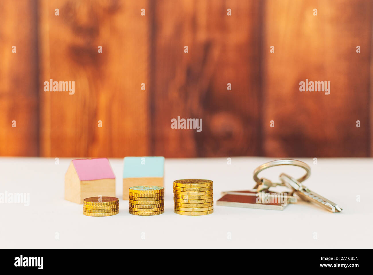 Miniature colorful houses with stack coins on a wooden background using as property and business ...