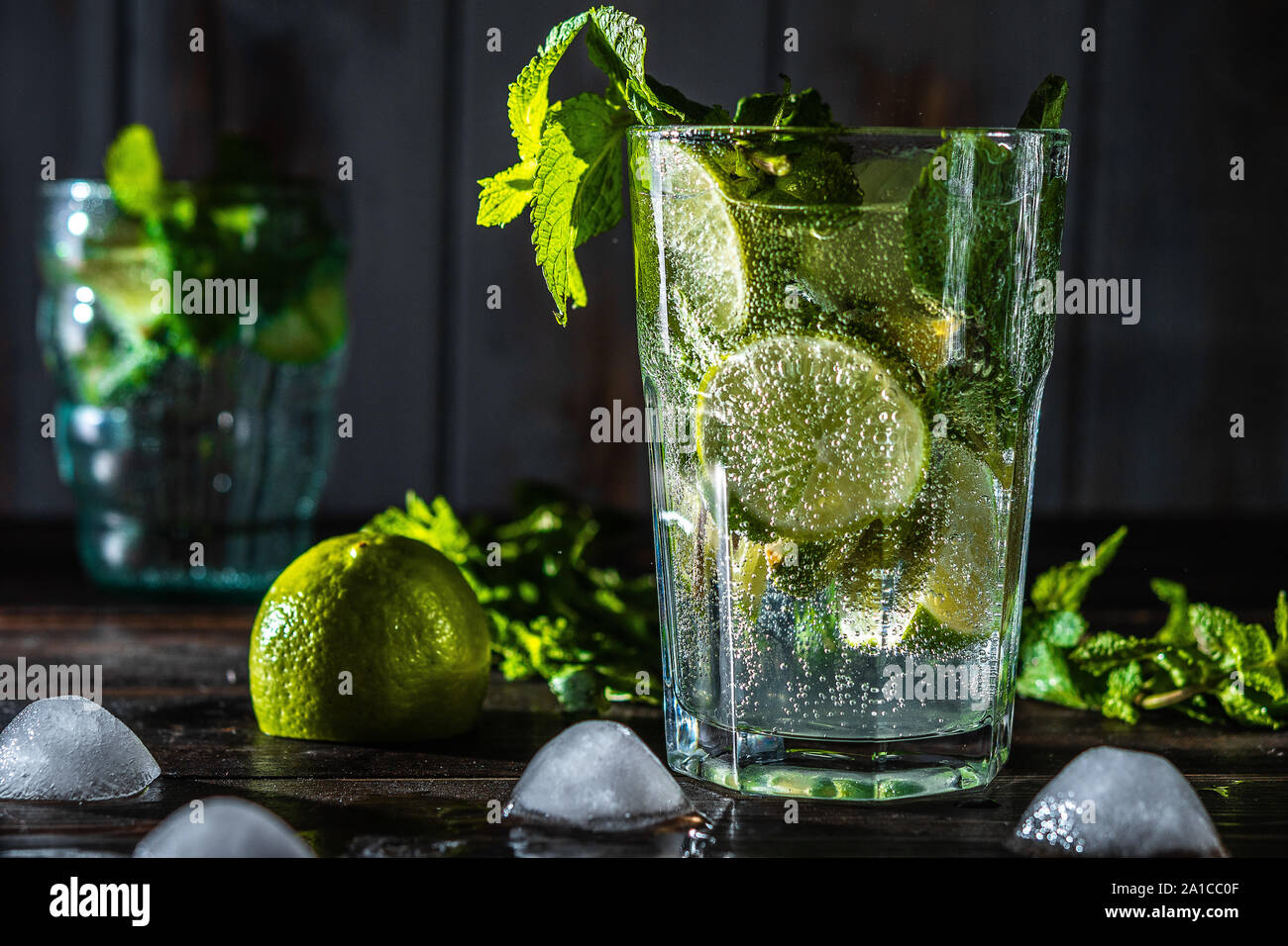 Mojito cocktail in a highball glass and ingredients on a rustic table ...