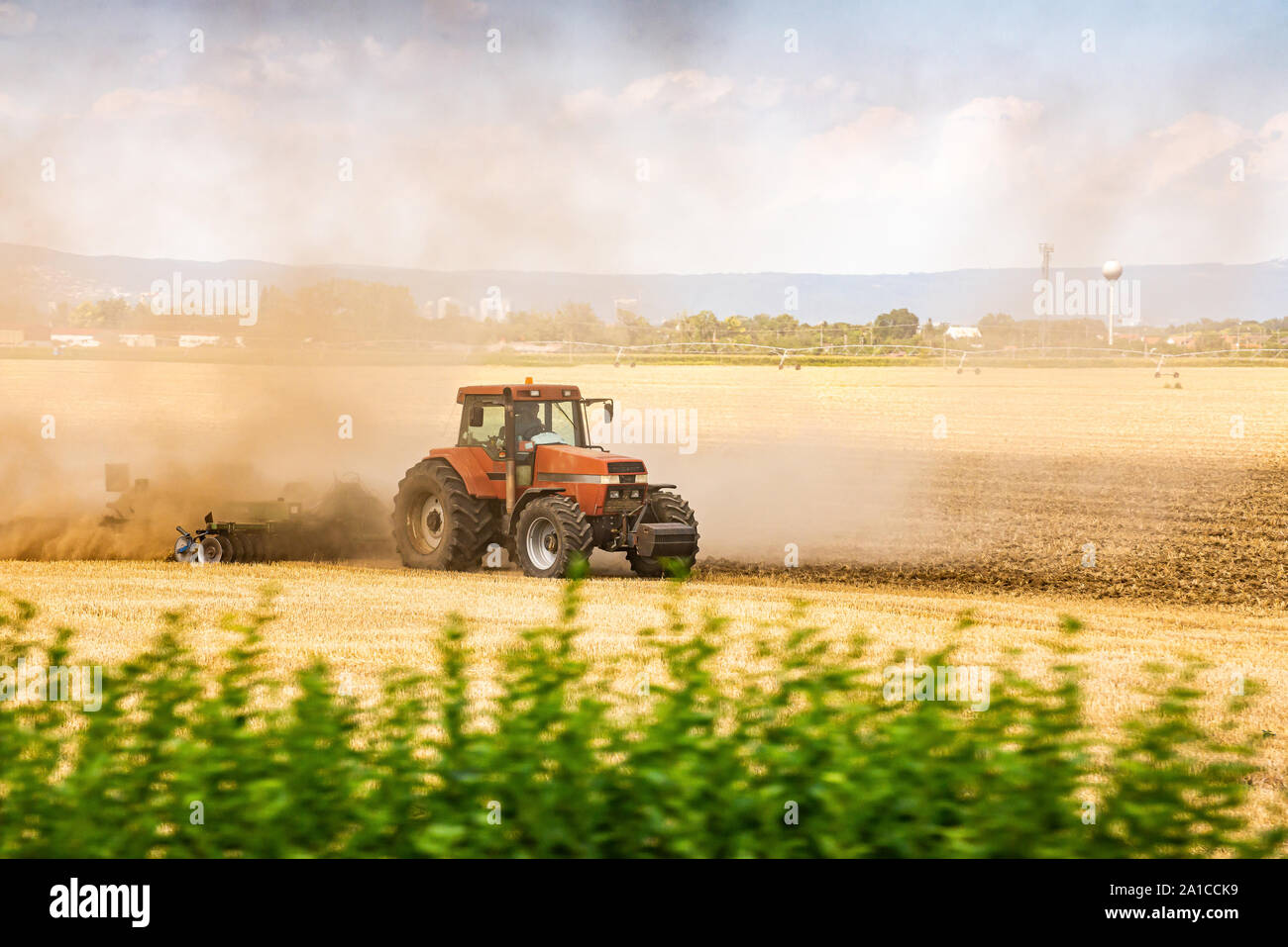 Tractor ploughing the field in sunset with dust in the air Stock Photo ...