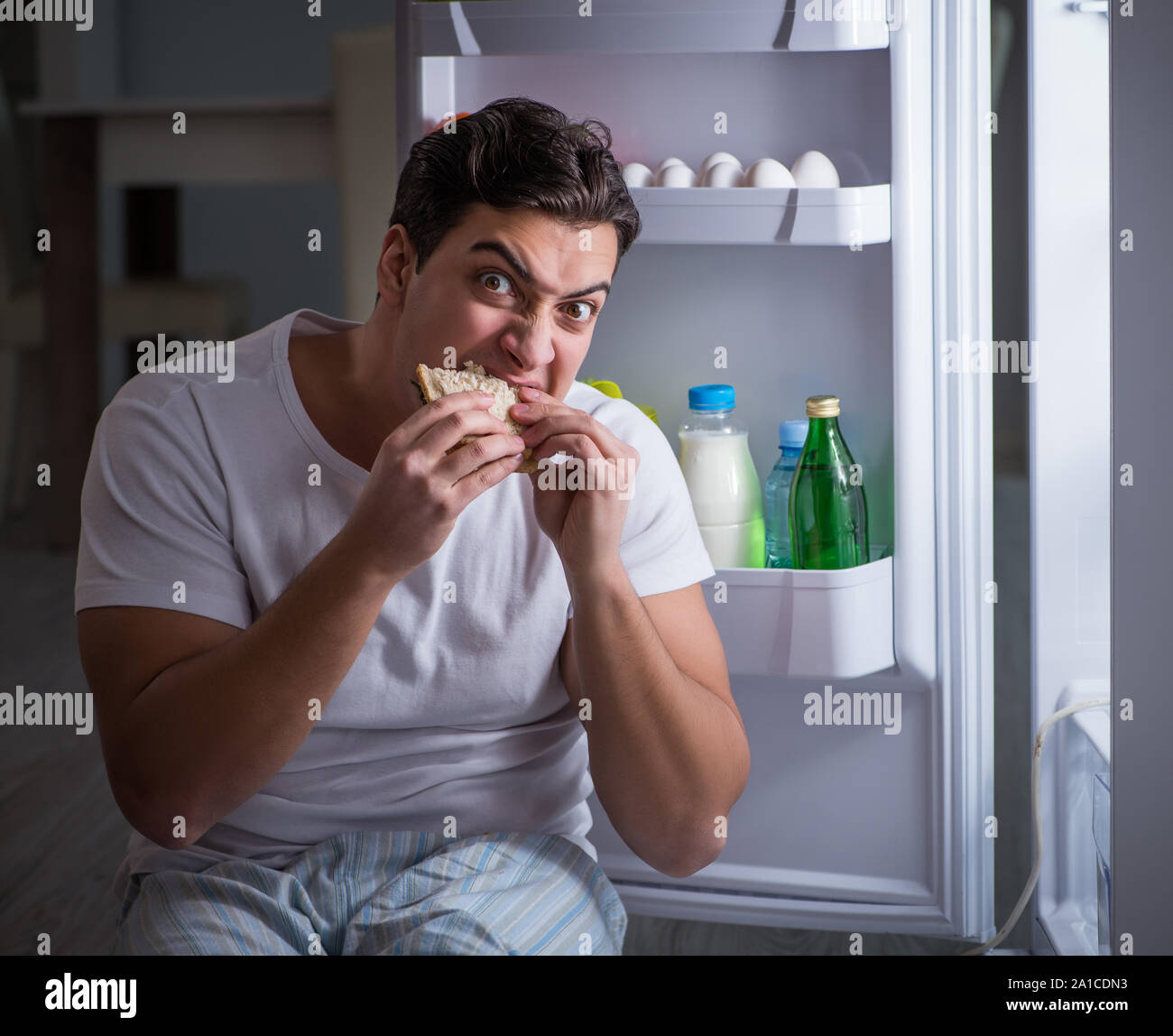 The man at the fridge eating at night Stock Photo - Alamy