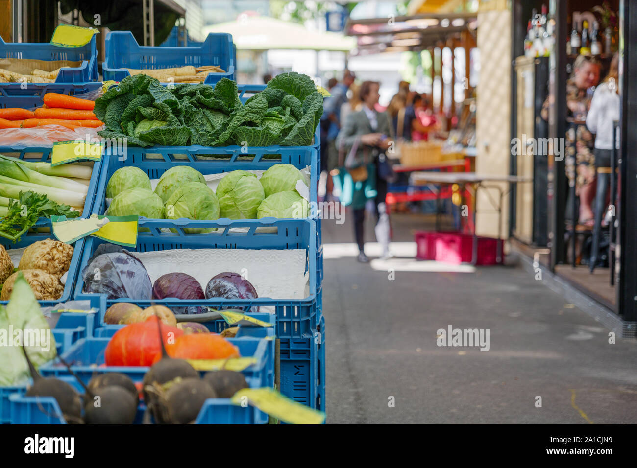 Various vegetables sell on row of blue plastic basket in front of stall ...