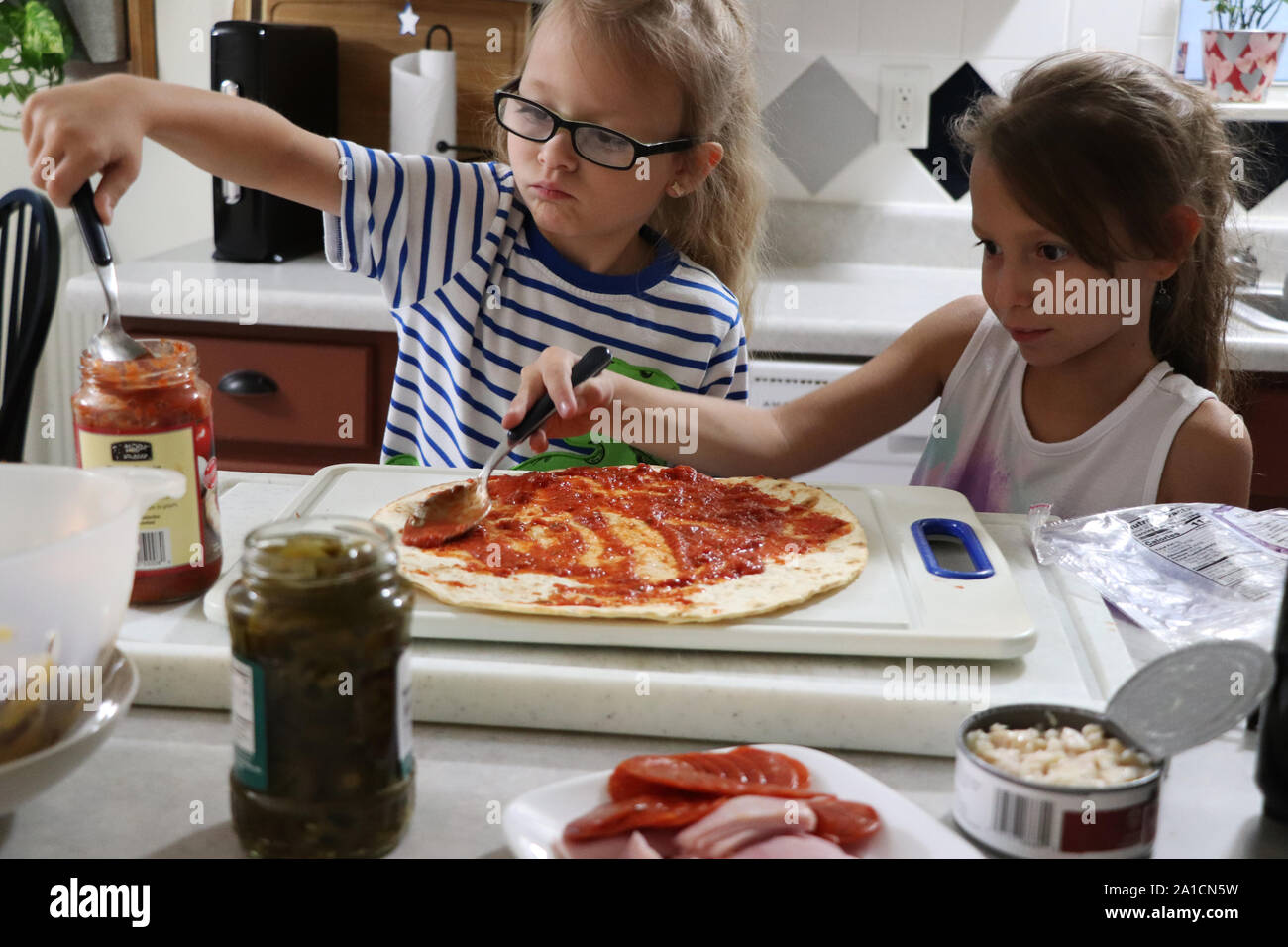 Two young sisters preparing their dinner together Stock Photo - Alamy