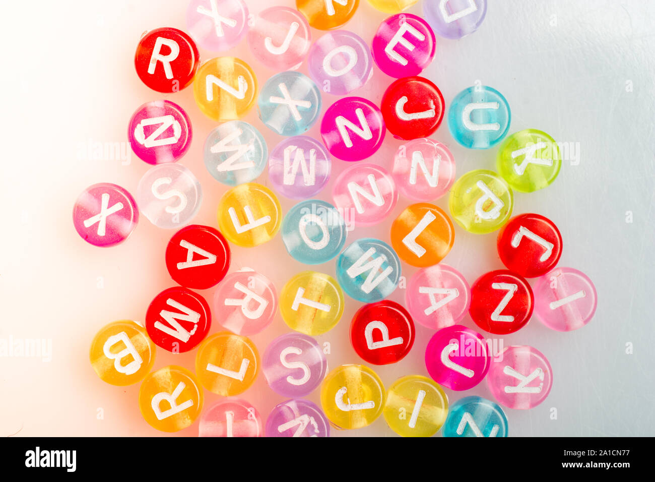 Multi color alphabet letter beads placed randomly on white background ...
