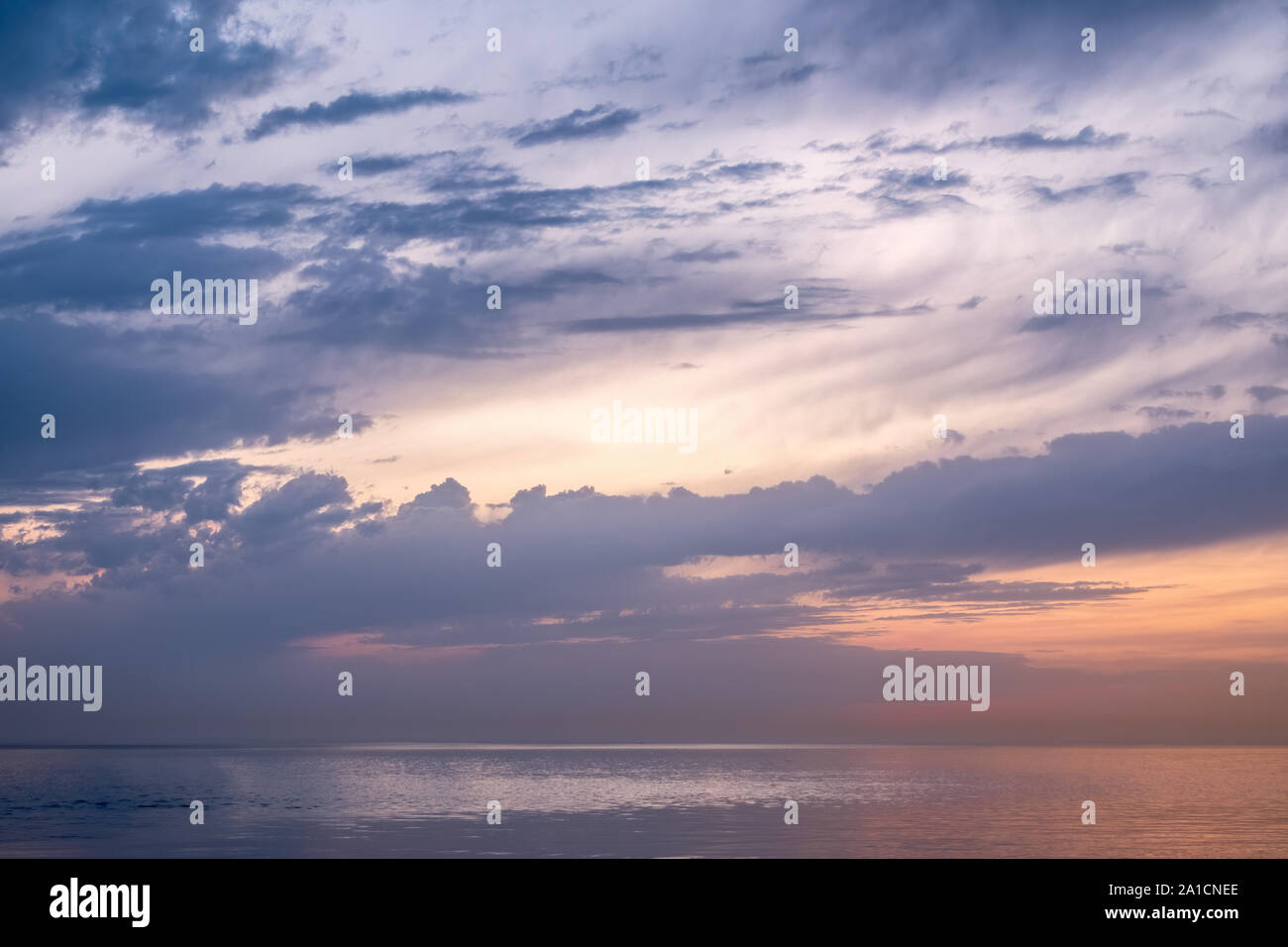 Beautiful pink sunset over the sea in a cloudy sky Stock Photo - Alamy