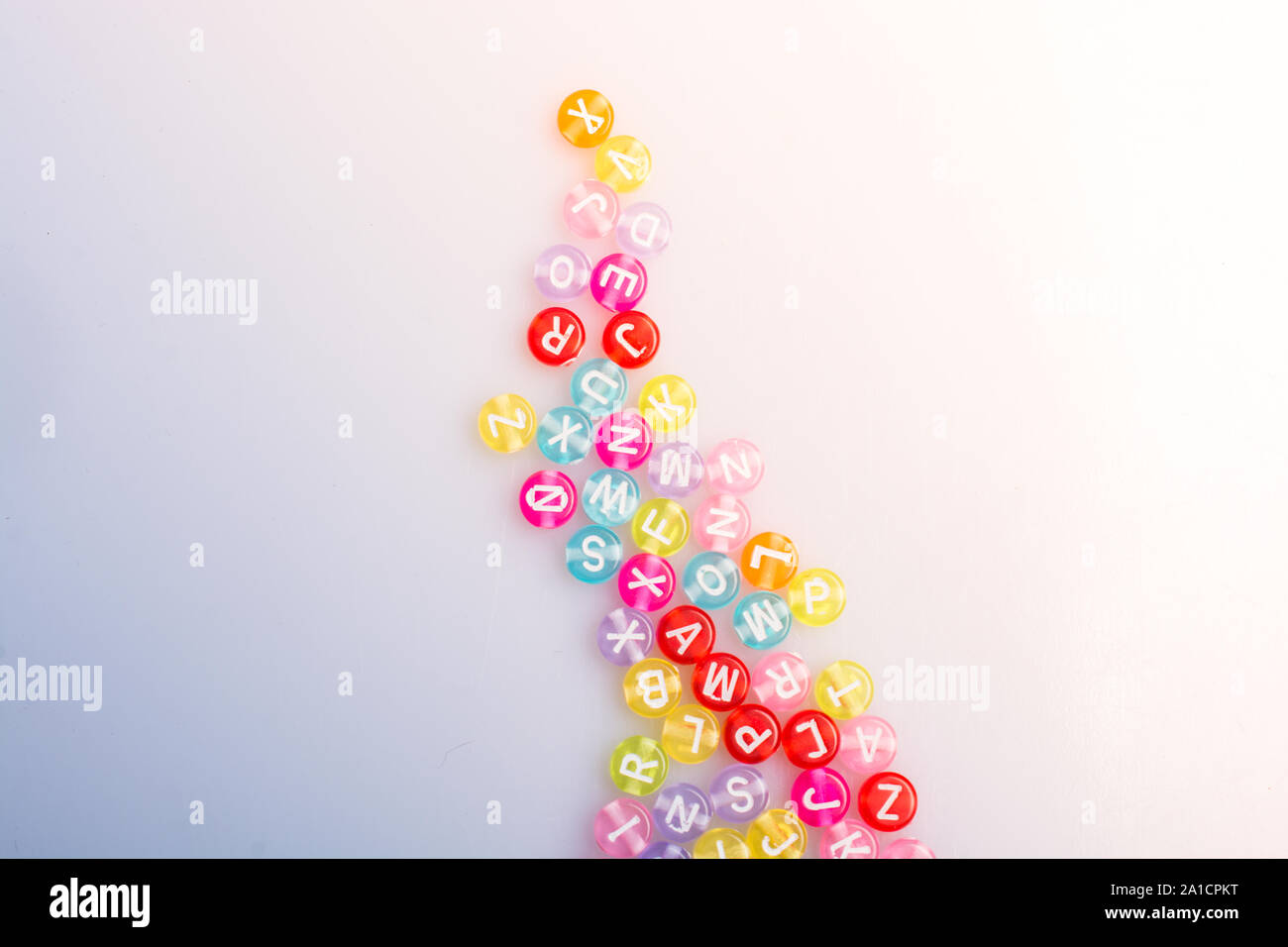 Multi color alphabet letter beads placed randomly on white background ...