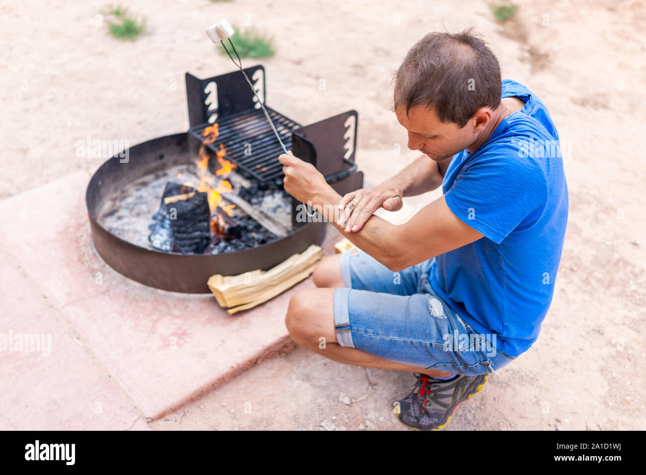 Young man roasting white marshmallow on fire in campground campfire ...