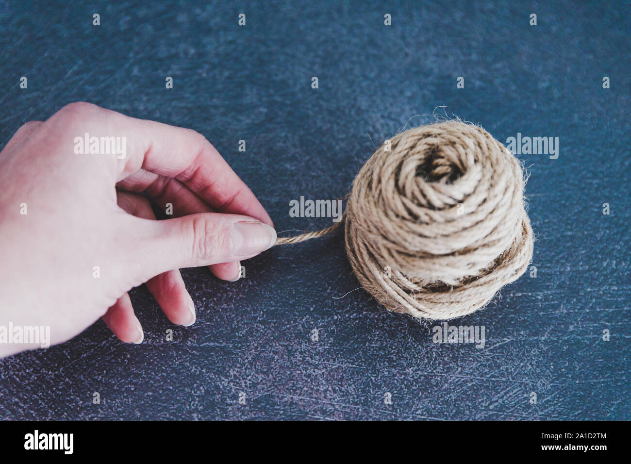 woman's hand untangling ball of thread by pulling string, complex of ...