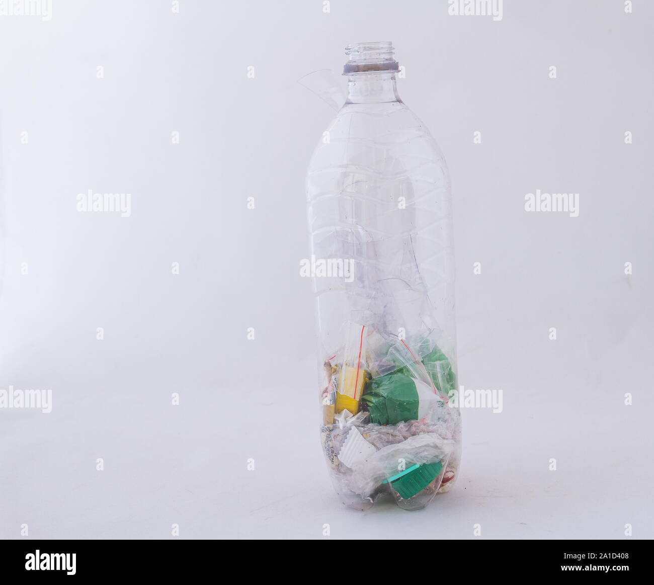 An empty plastic bottle with discarded single use plastic litter in it ...