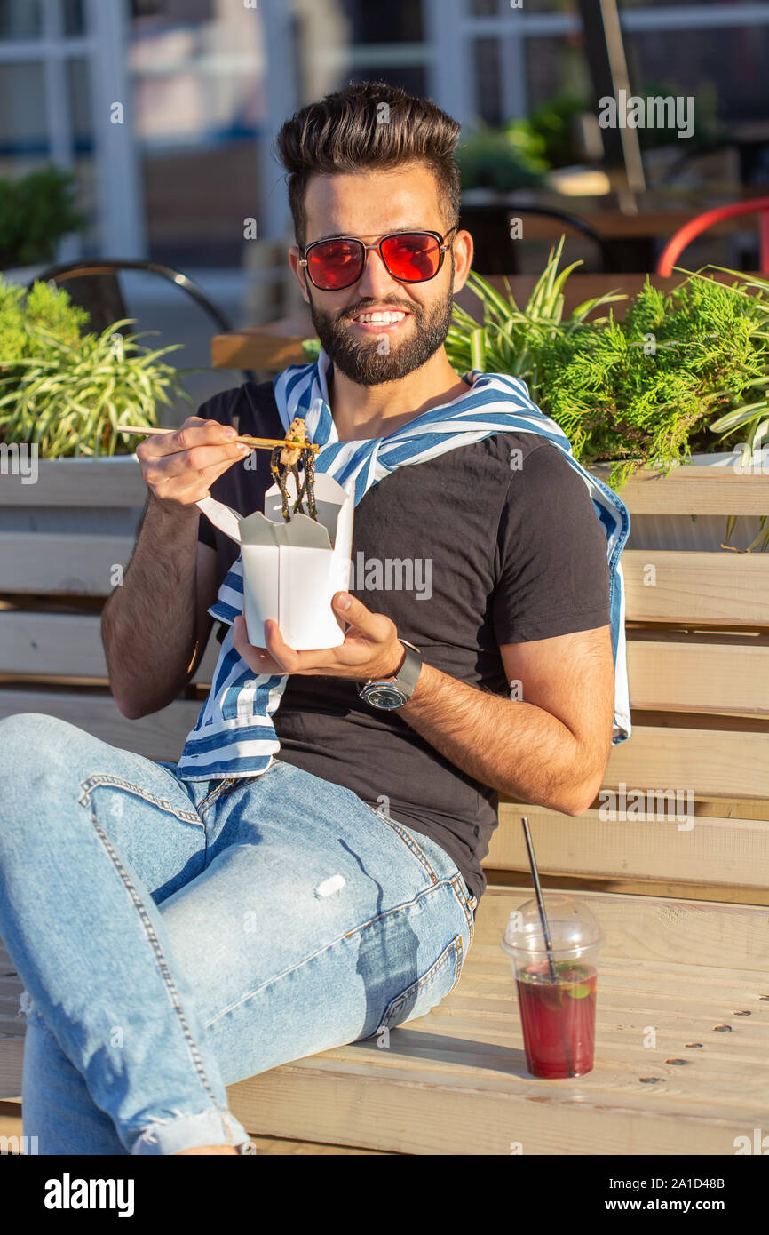 Handsome young arab man are holding wooden sticks chinese noodle ...