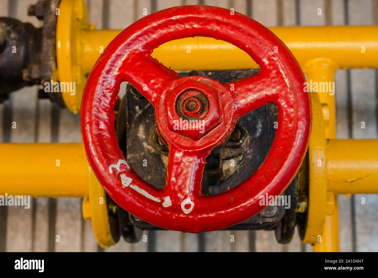 Red round valve on a background of yellow pipes Stock Photo - Alamy