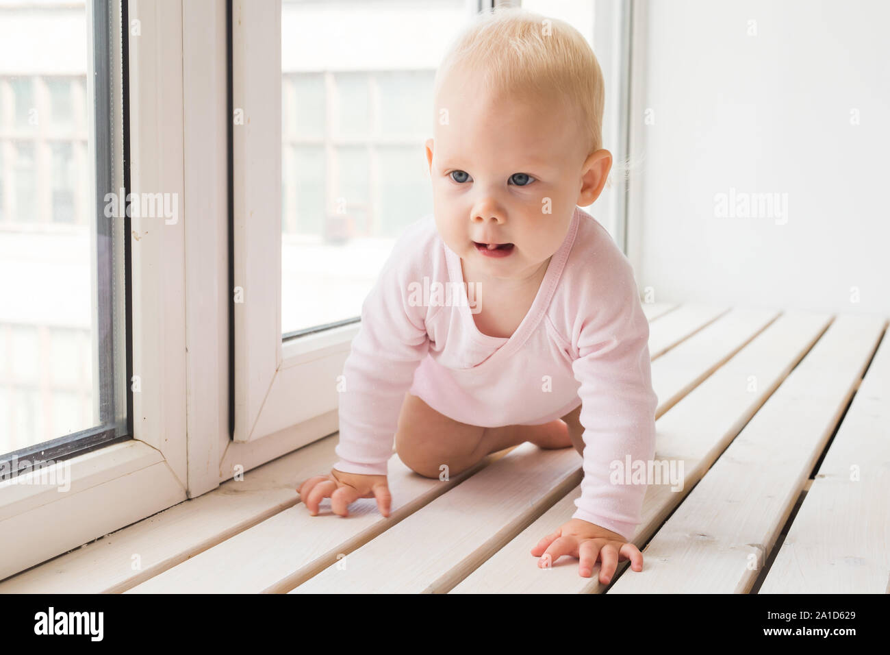 Childhood, family and infant concept - Little baby girl on windowsill ...