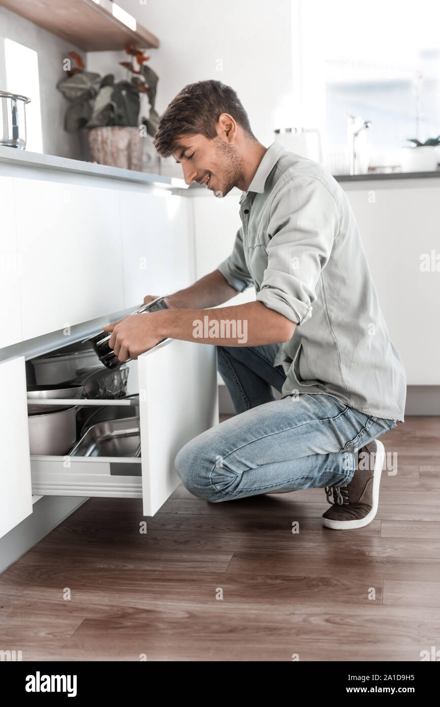 attractive man taking plates out of the kitchen table Stock Photo - Alamy