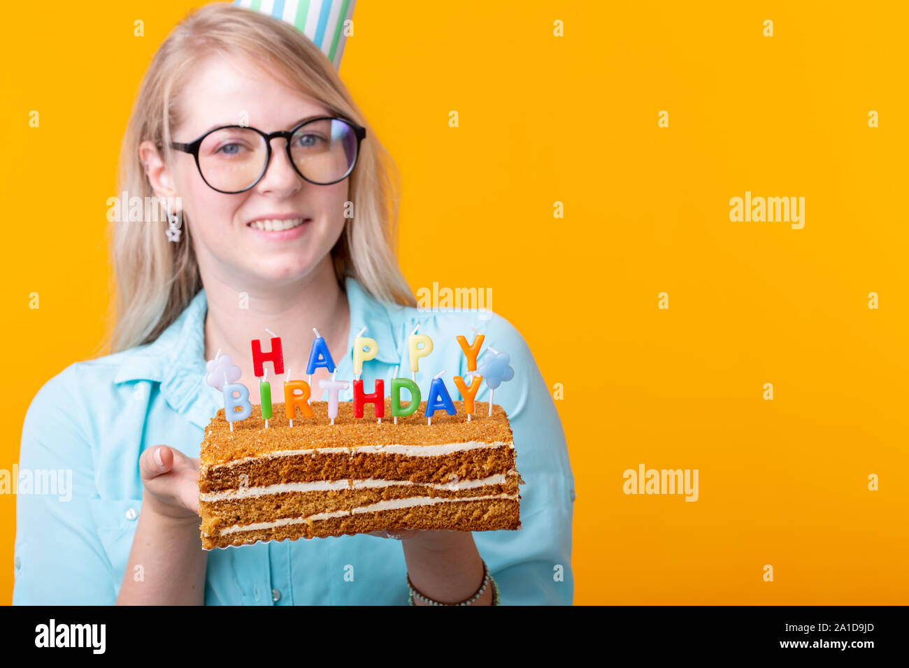 Positive funny young woman with a cap and a homemade cake in her hands ...