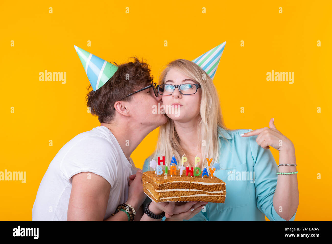 Cheerful young couple charming guy and cute girl in paper hats make ...