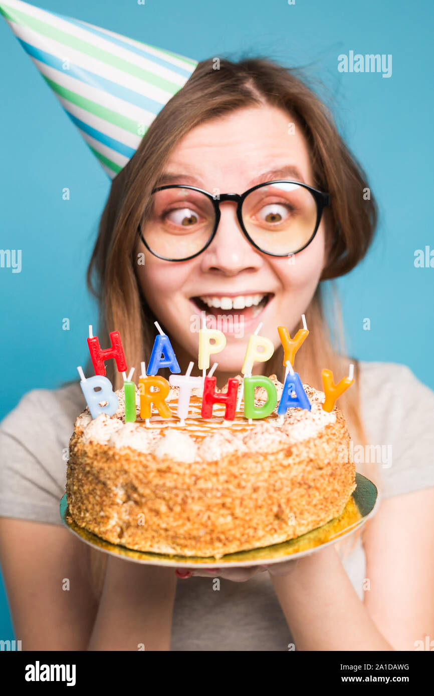 Crazy funny girl in a paper hat and glasses holding a big birthday cake ...