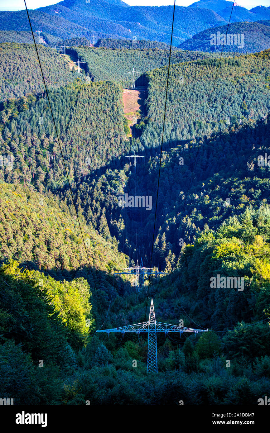 Germany, a high voltage powerline running trough a valley covered with ...