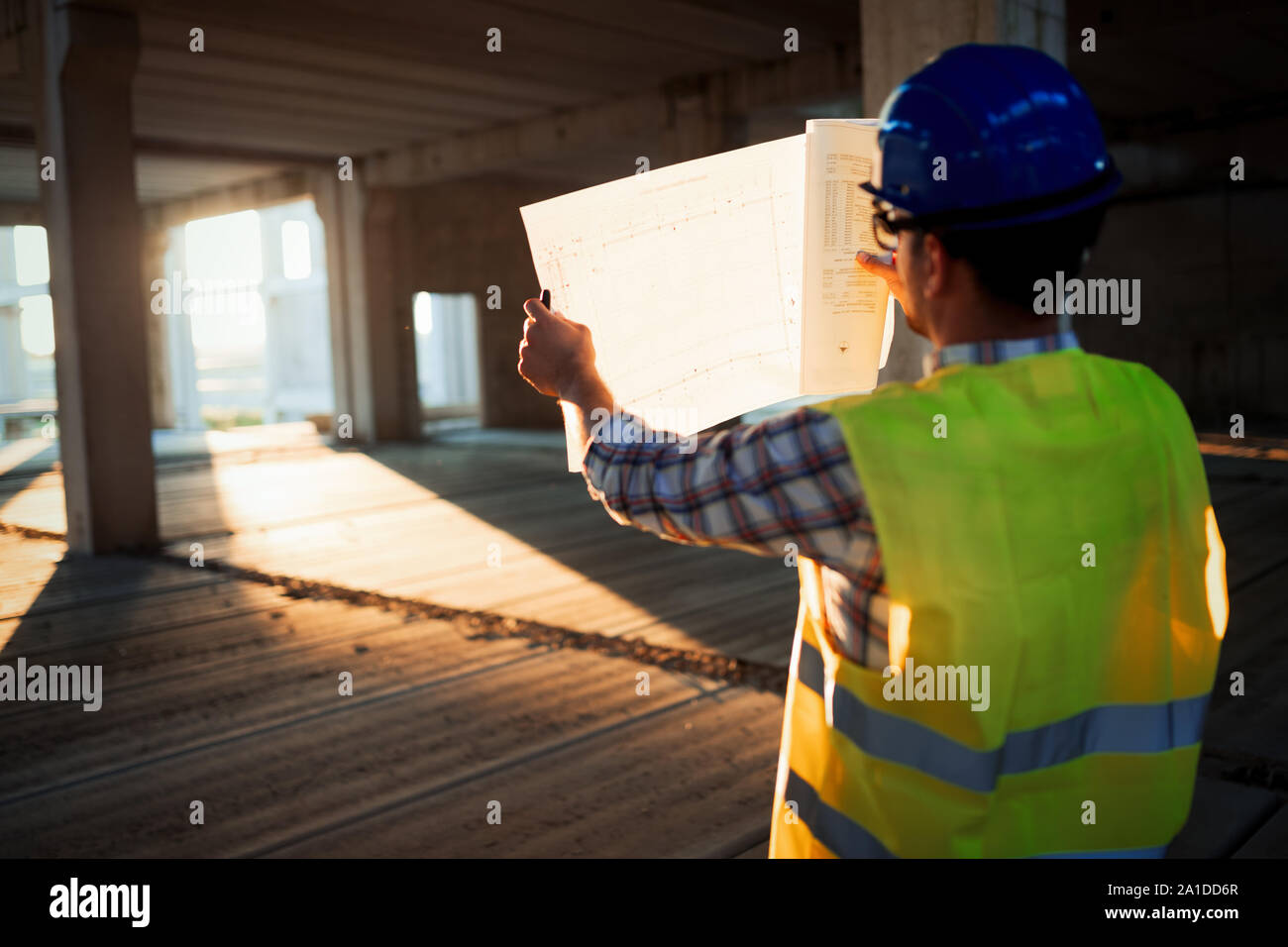 Engineer working on construction site and holding blueprint Stock Photo ...