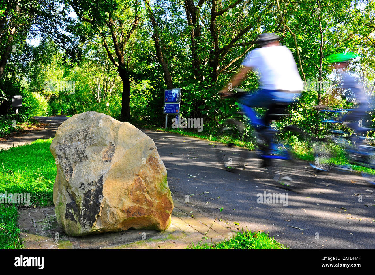 Two cyclists passing large boulder on the Preston Guild Wheel circuit ...